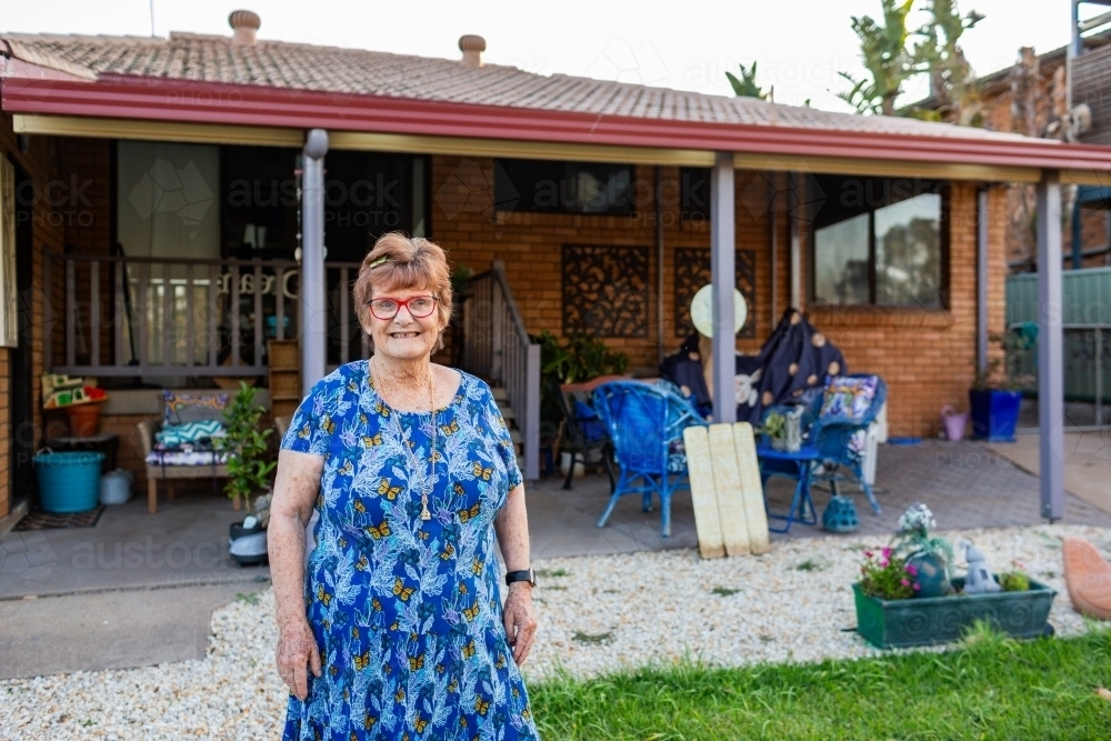 Image of Portrait of happy older woman in blue dress in backyard of ...