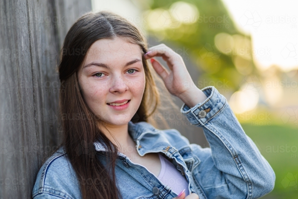 Image of Portrait of happy teenage girl leaning on wooden backyard ...