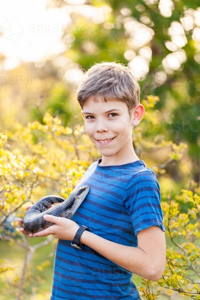 Image of Portrait of happy tween boy with lizard outside in spring ...