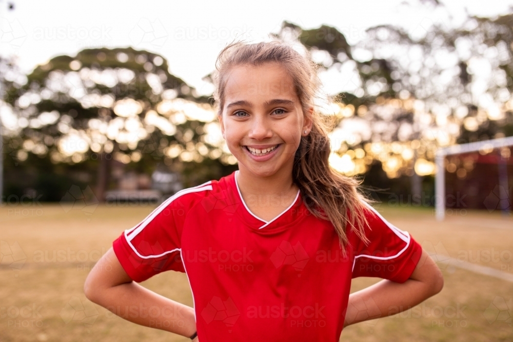 Image of Portrait of single tween girl football player wearing a red sports uniform - Austockphoto