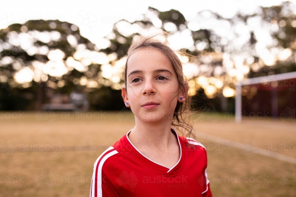 Image of Portrait of single tween girl football player wearing a red sports uniform - Austockphoto