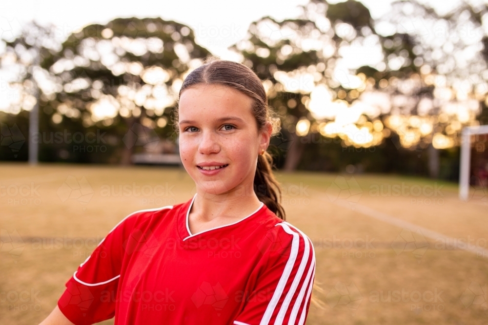 Image of Portrait of single tween girl football player wearing a red sports uniform - Austockphoto