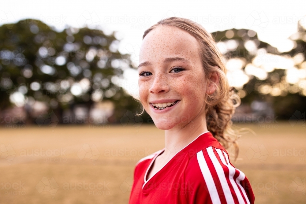 Image of Portrait of single tween girl football player wearing a red sports uniform - Austockphoto