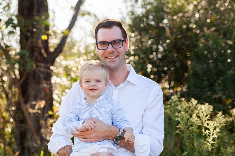Image of Portrait of smiling father holding young son outside ...