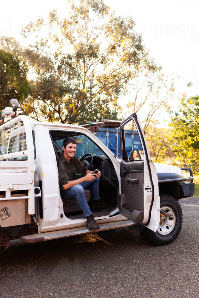 Image of Portrait of smiling teenaged young man sitting in his ute ...