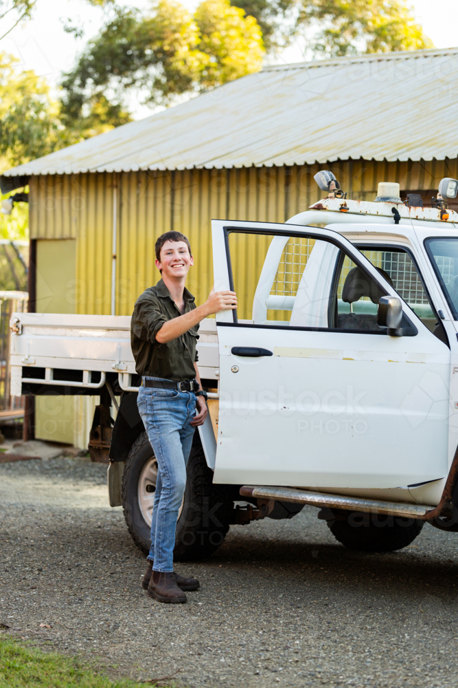Image of Portrait of teenaged young man standing with his first car a ...