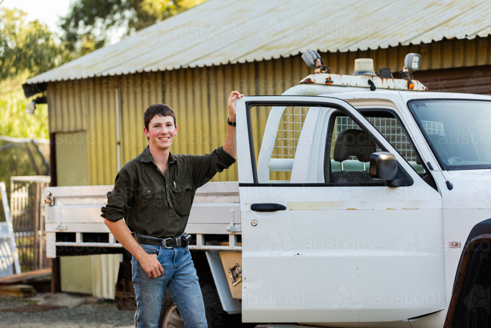 Image of Portrait of teenaged young man standing with his first car a ...