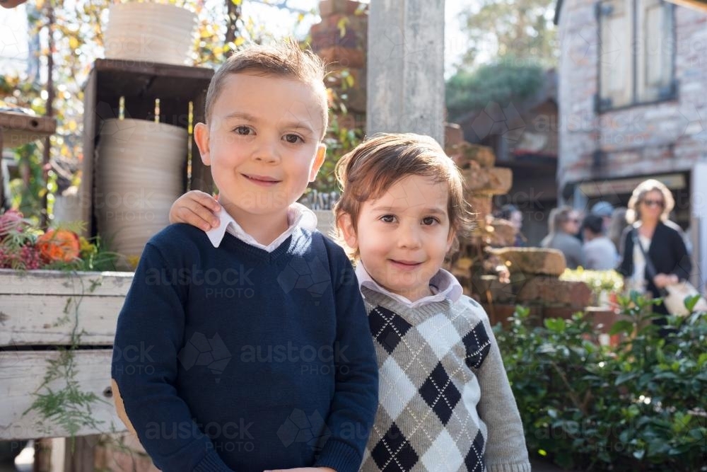 Image of Portrait of two happy brothers in a rustic garden - Austockphoto