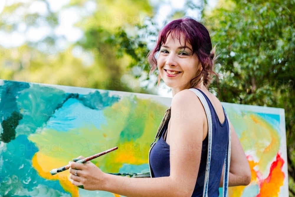 Image of portrait of young australian artist beside painting outdoors ...