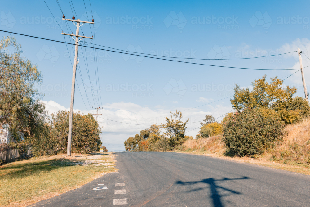 Image of Power lines in small town casting shadows on the road ...
