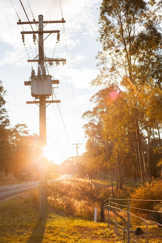 Image of Power pole and wires beside rural road at sunset with light ...