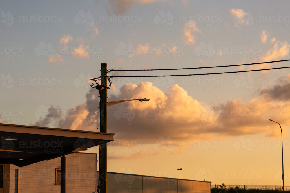 Image of powerline and pole at sunset with clouds behind buildings in ...