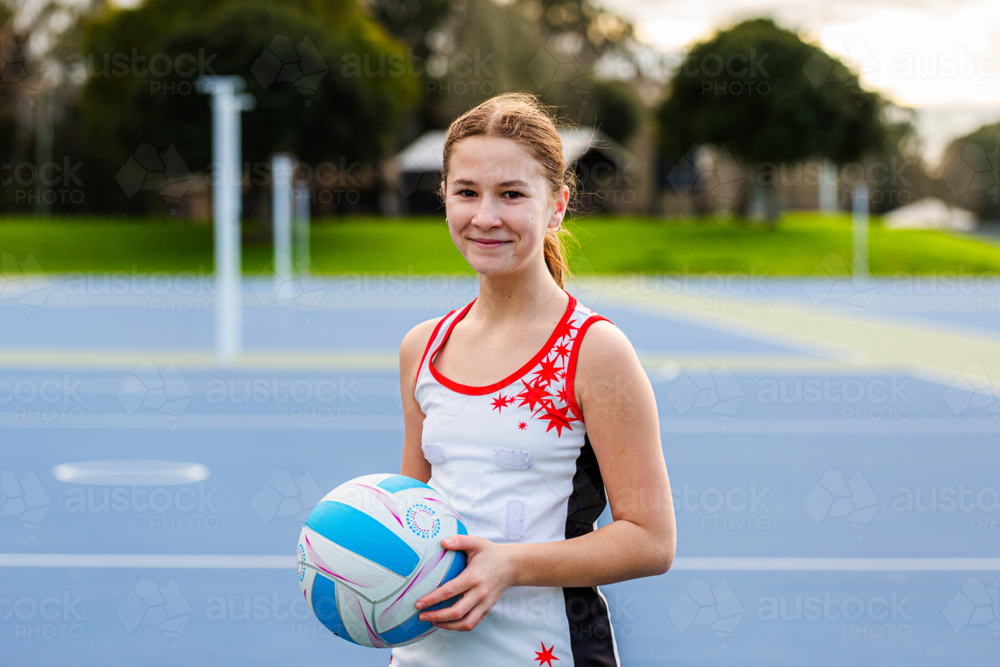 Image of pre-teen netball player with ball on court training for sport ...