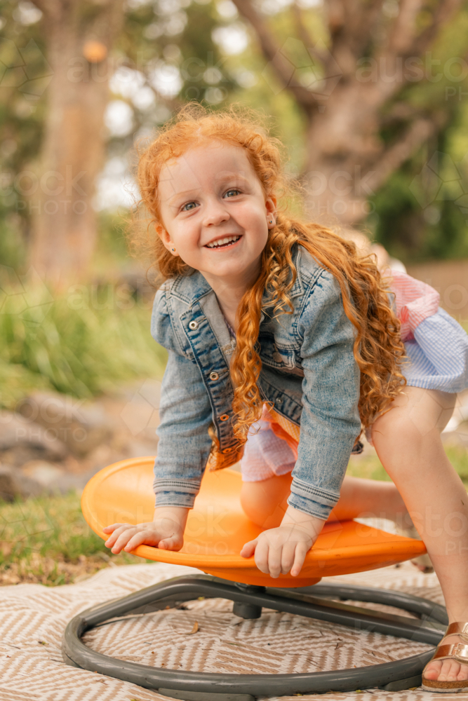 Image of Preschool age girl with long red hair spinning on play ...