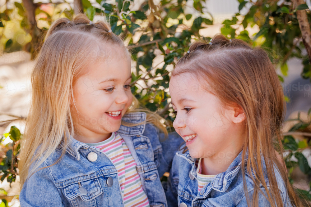 Image of Preschooler sisters sitting together on garden edge at ...