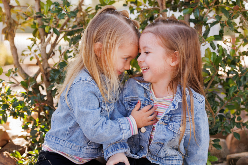 Image of Preschooler sisters sitting together on garden edge at ...