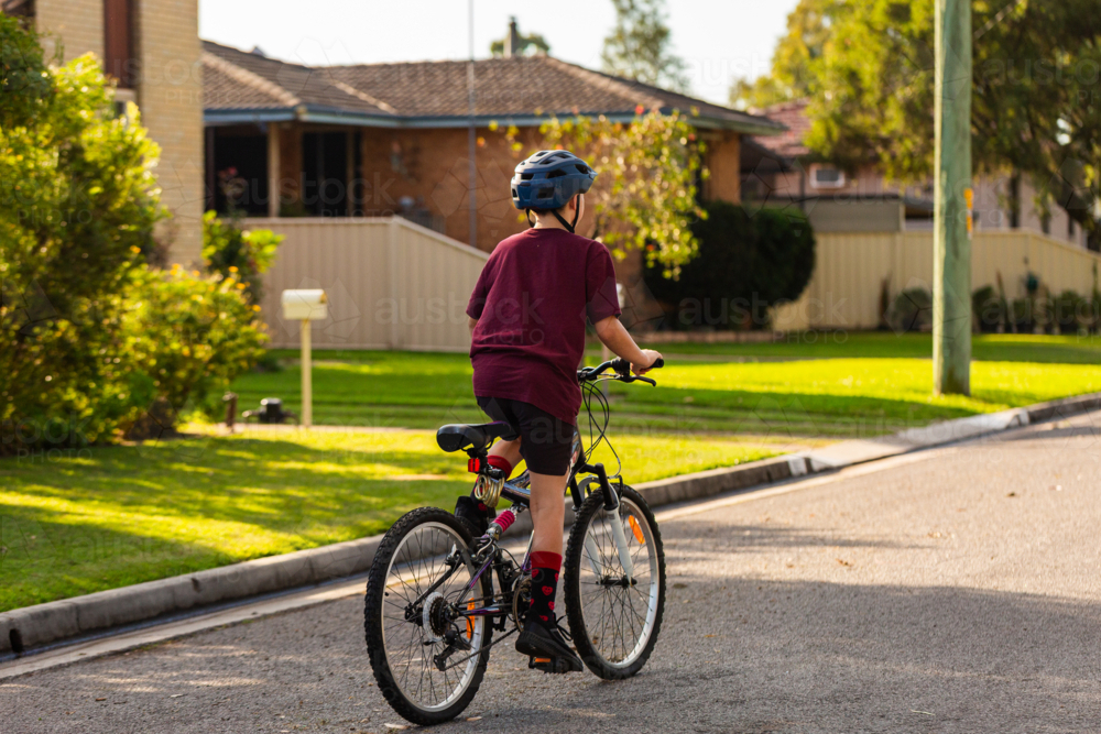 Image of Preteen aussie kid riding past on sunny afternoon in town ...