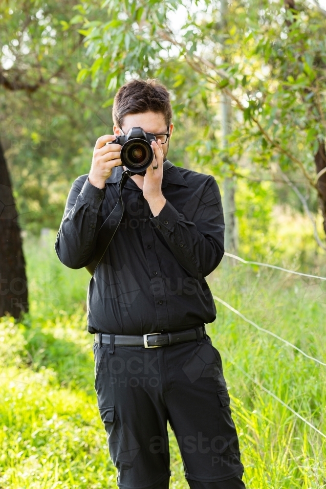 Image of Professional male photographer in black standing outside with ...