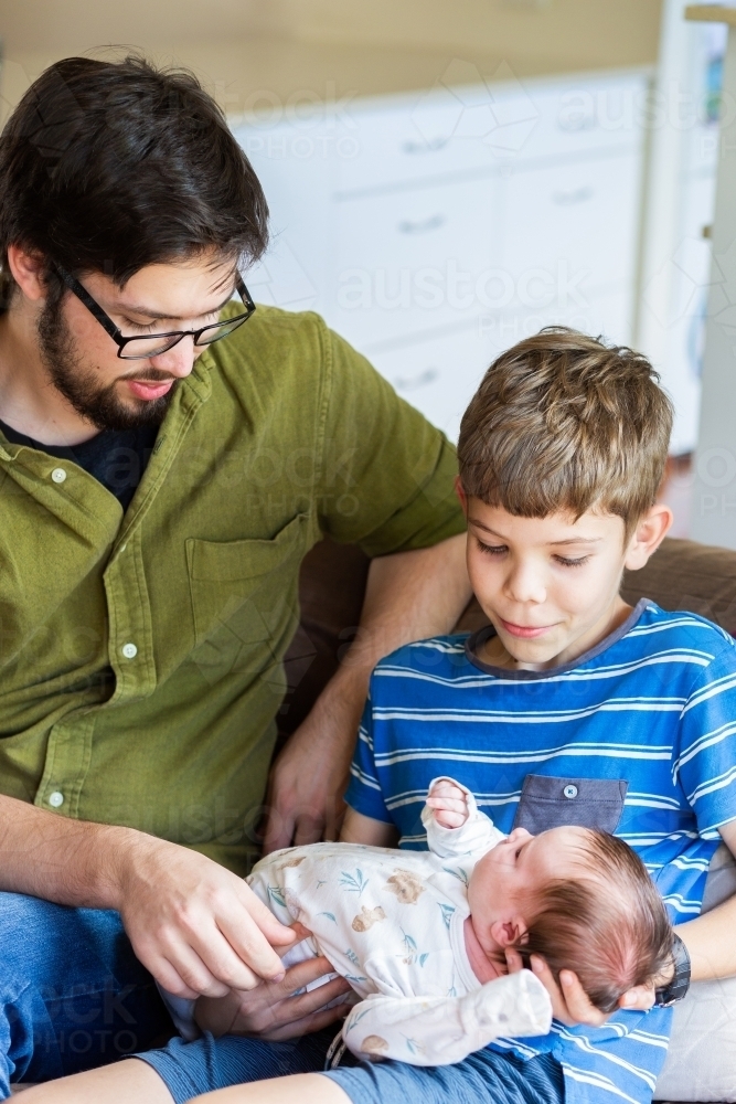 Image of Proud dad introducing newborn baby to young uncle - family ...