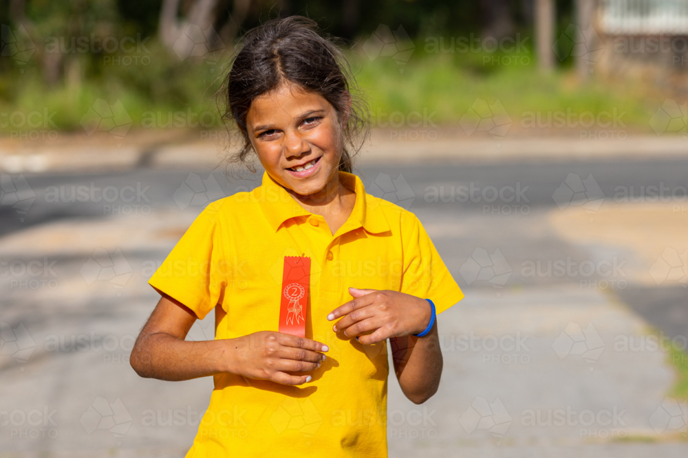 Image of proud school student showing off second place ribbon after ...