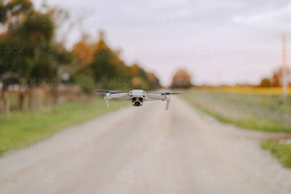 Image of Quadcopter drone hovering over quiet country road, modern ...
