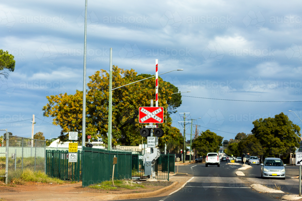 Image of Railway crossing with boom gate lifted and cars passing along ...