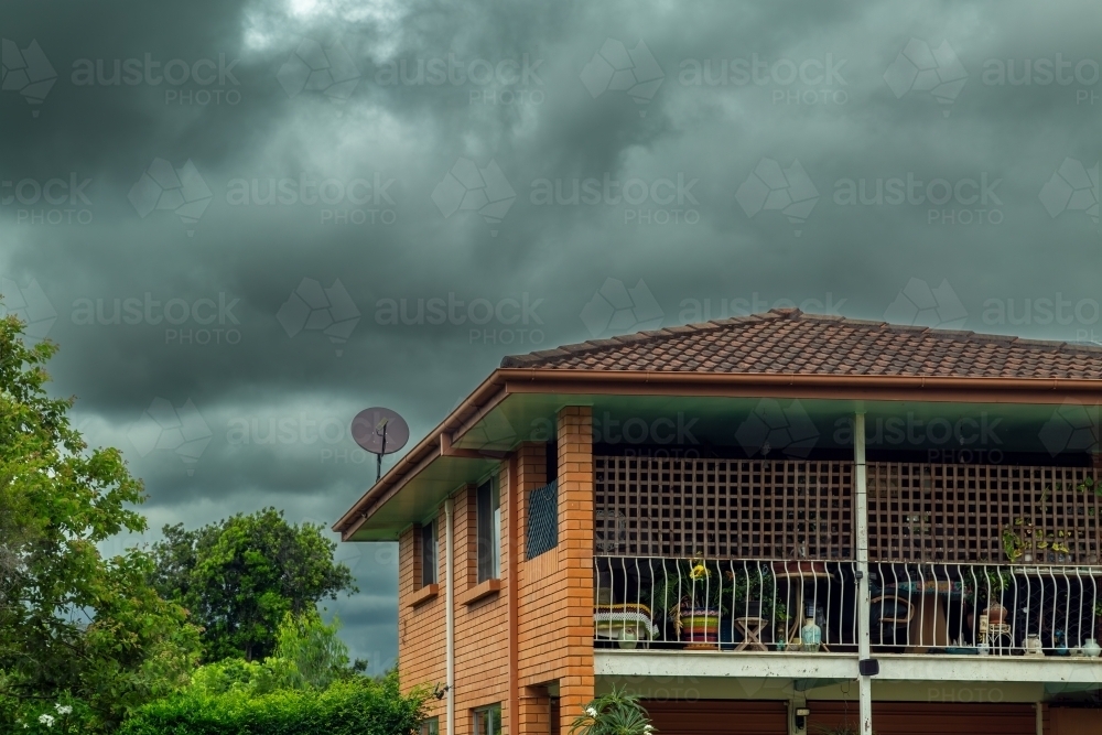 Image of Rain and storm clouds and suburban brick house - Austockphoto