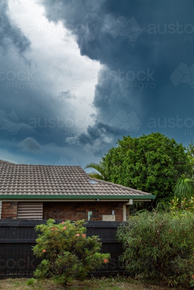 Image of Rain and storm clouds and suburban brick house - Austockphoto