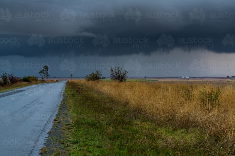 Image of Rain falling from a dramatic stormfront over rural farmland ...