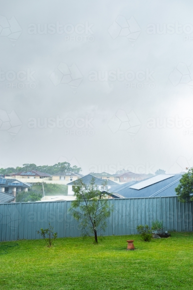 Image of Rain falling over suburban backyard and rooftops with solar ...