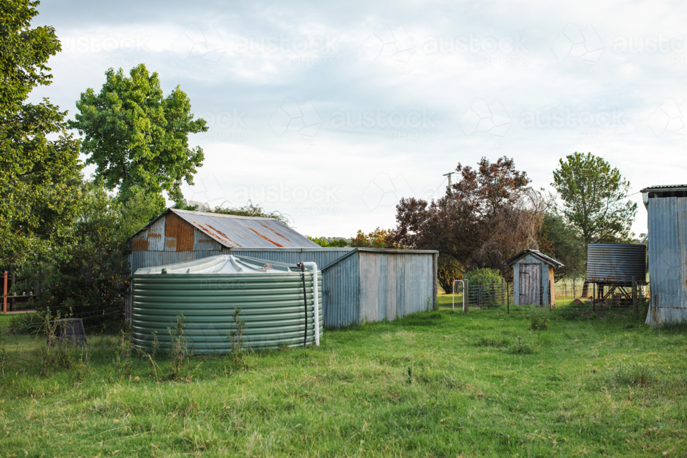 Image of Rain water tank beside shed on rural farm property - Austockphoto