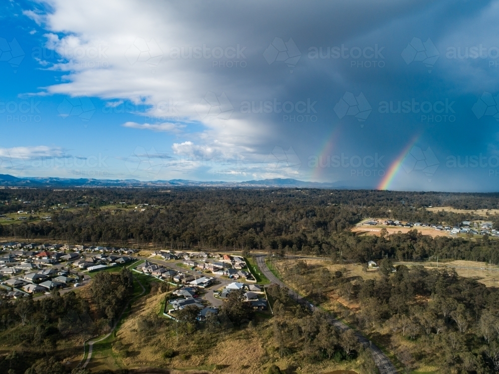 Image of rainbow in distant rain cloud formation above housing ...