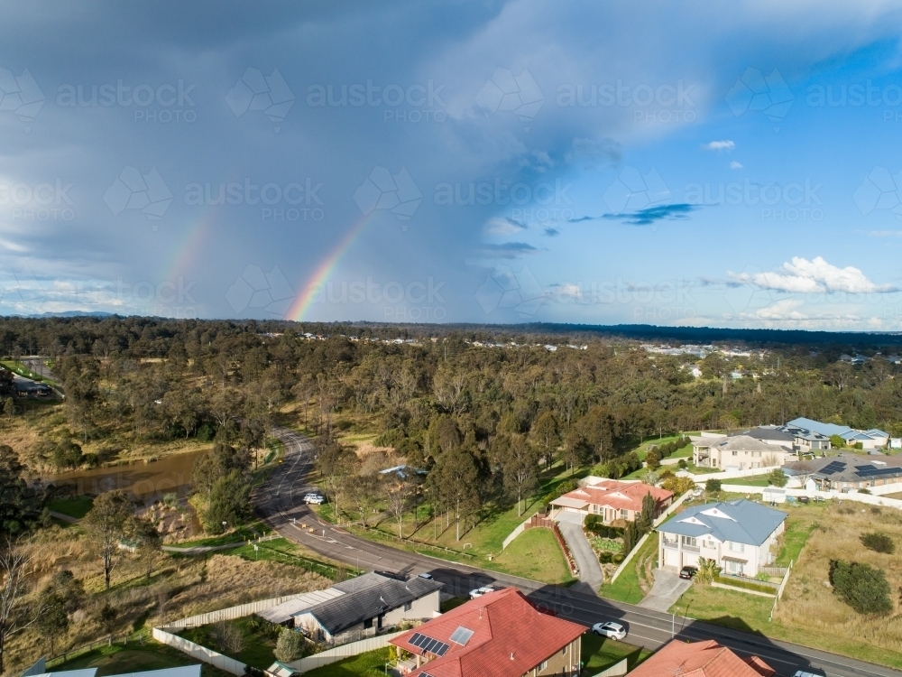 Image of rainbow in distant rain cloud formation above housing ...