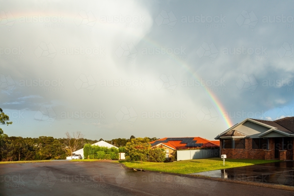Image of Rainbow over houses and solar panels on roof - Austockphoto