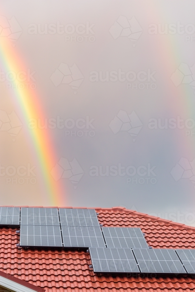 Image of Rainbow over roof of house with solar panels shining after ...
