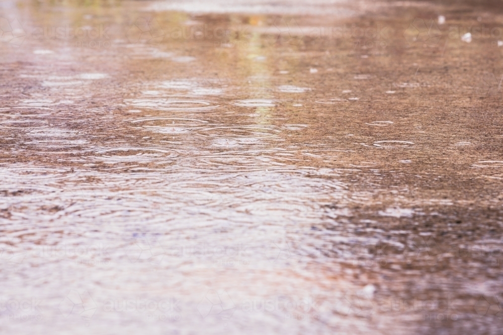 Image of raindrops falling on a concrete surface - Austockphoto