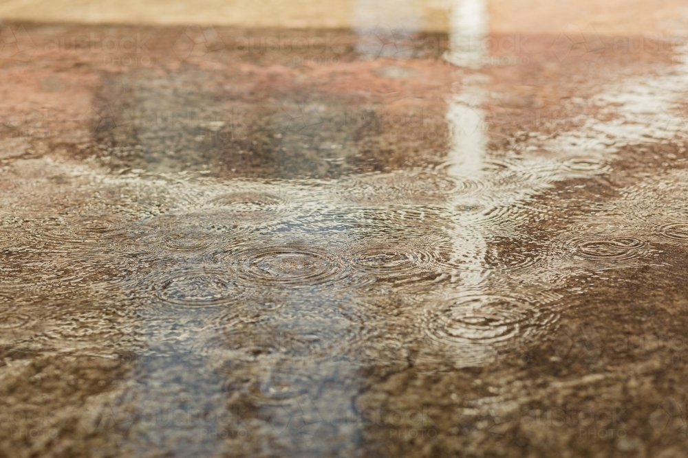Image of Raindrops splash in puddle on concrete driveway - Austockphoto