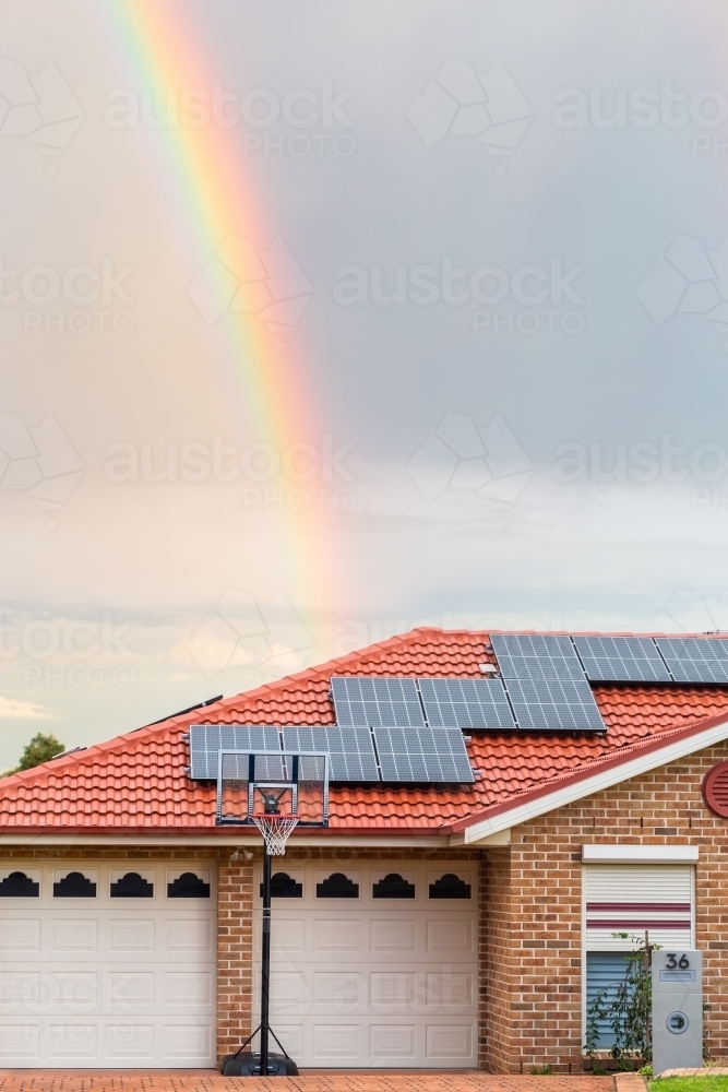 Image of rainy day rainbow over a home with solar - Austockphoto