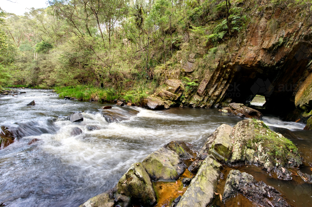 Image of Rapid stream flowing through basalt tunnel surrounded by ...