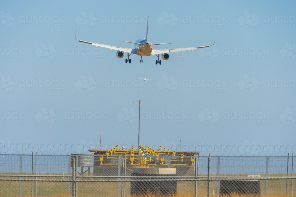 Image of Rear view of a large jet coming into land over runway landing ...