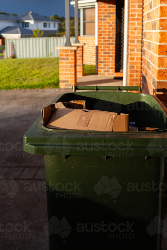 Image of Recycling bin outside brick home full of cardboard - Austockphoto