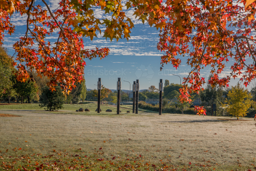 Image of Red autumn leaves framing a country scene under blue skies, a ...