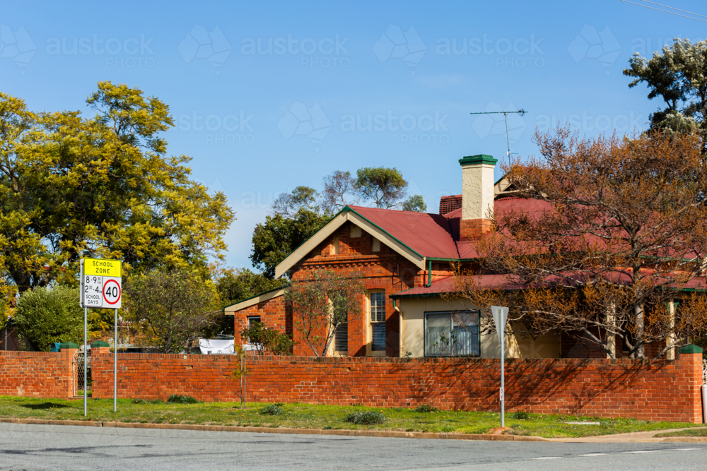 Image of Red brick fence with red building behind on sunlit day in ...