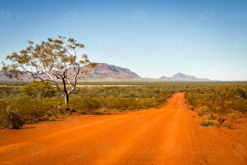 Image of Red dirt road leading toward distant ranges under a clear blue ...