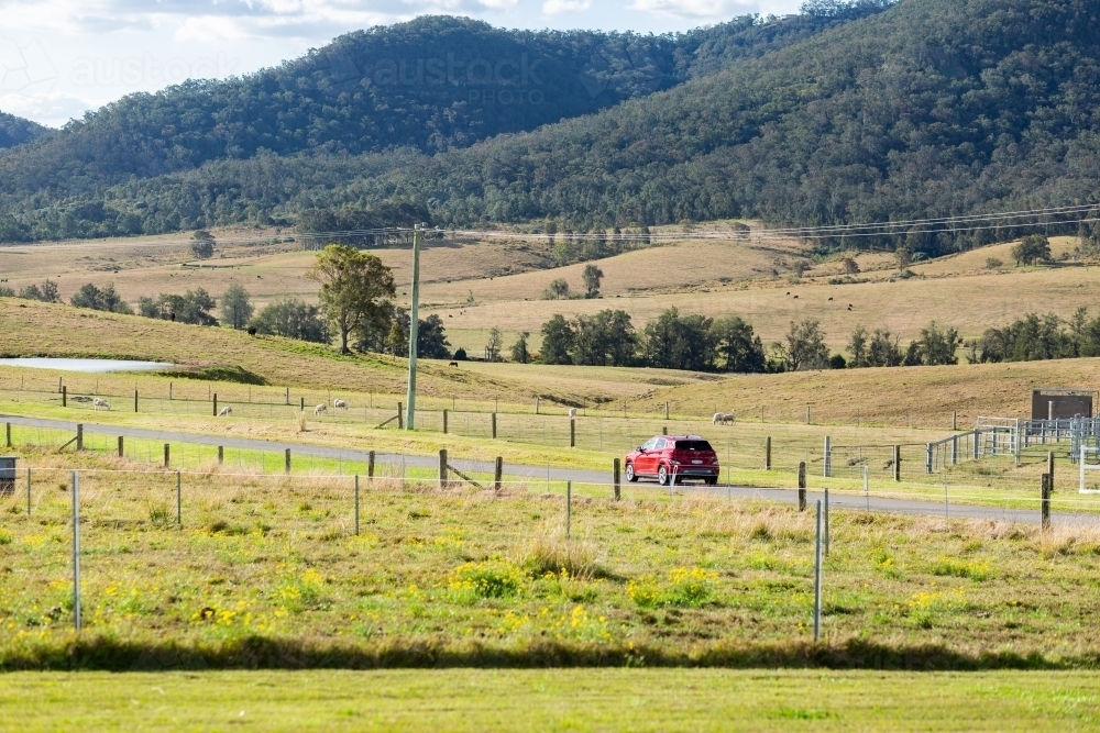 Image of Red electric vehicle car driving down rural country road on ...