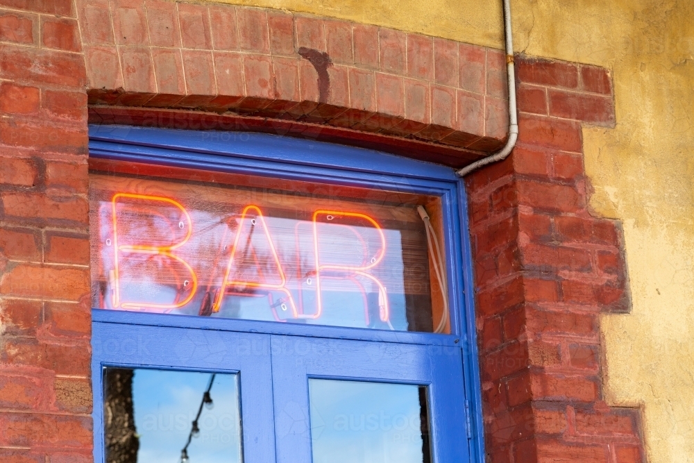 Image of Red neon bar sign above blue door and brick and limestone ...