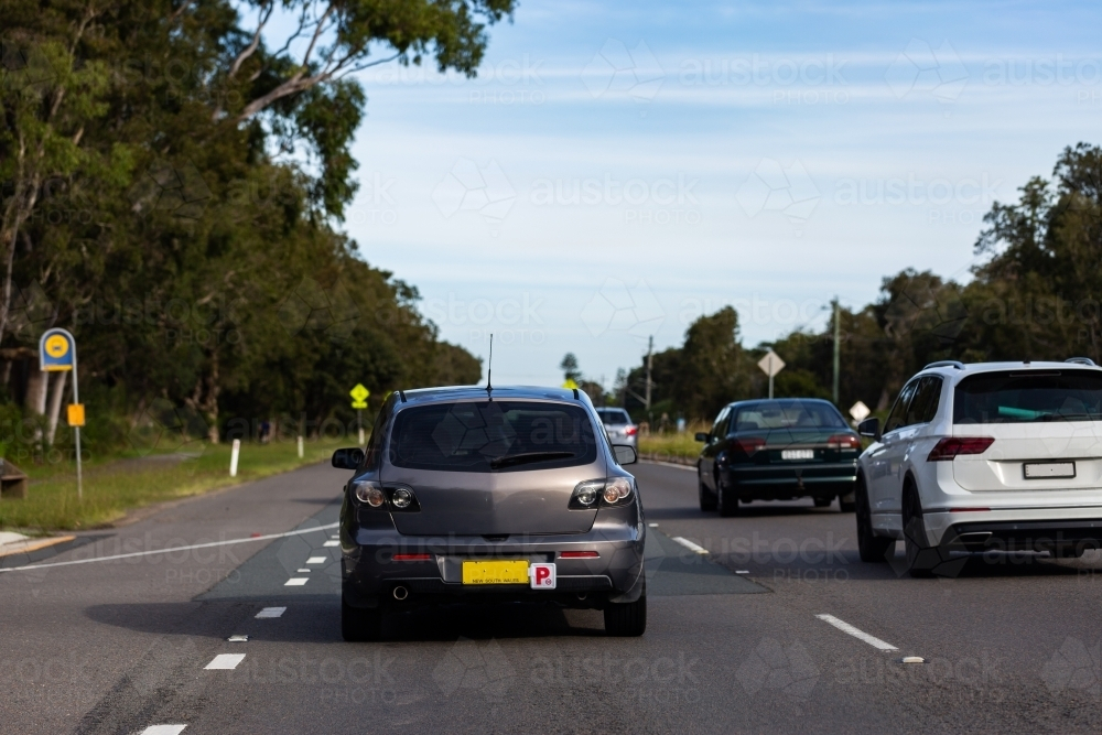 Image of Red p plate on car traveling down road - Austockphoto