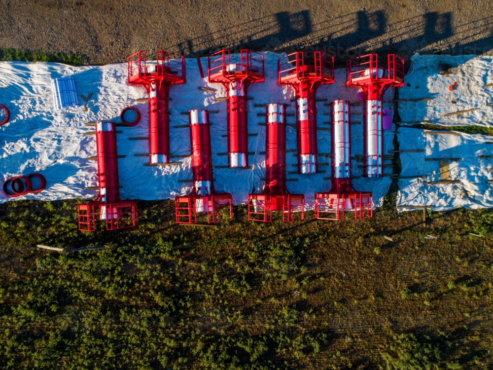 Image of red structural pylons lying on ground for highway bypass under ...