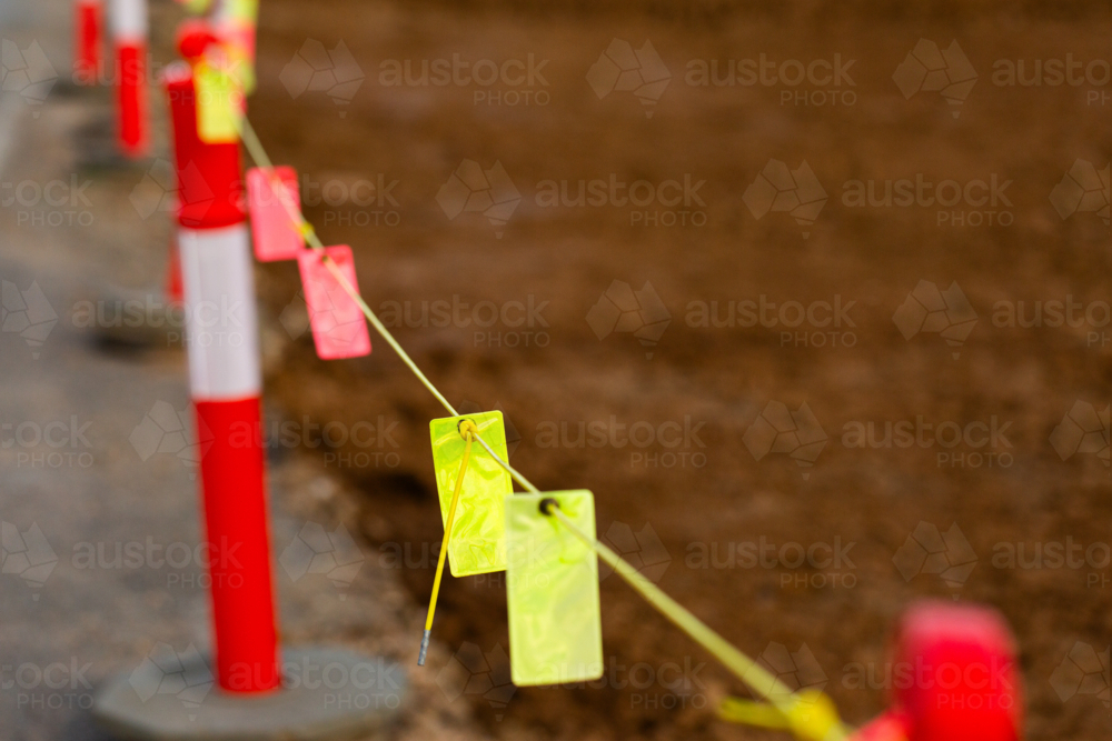 Image of Reflective tags on worksite fence beside road - Austockphoto