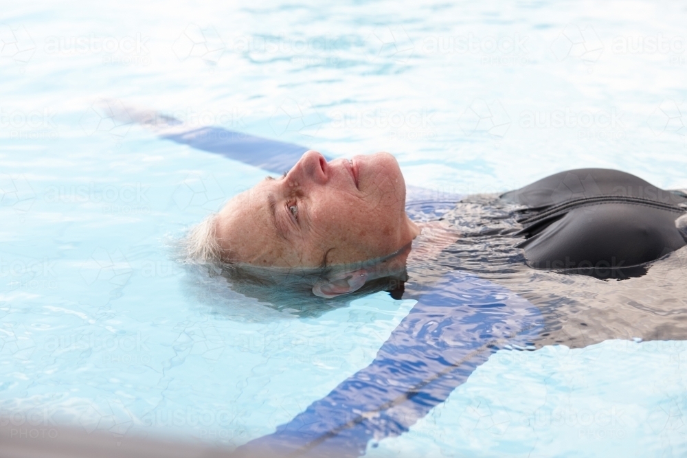 Image of Relaxed active senior lady floating in swimming pool ...